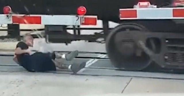 Man rolls under moving freight train - CBS News